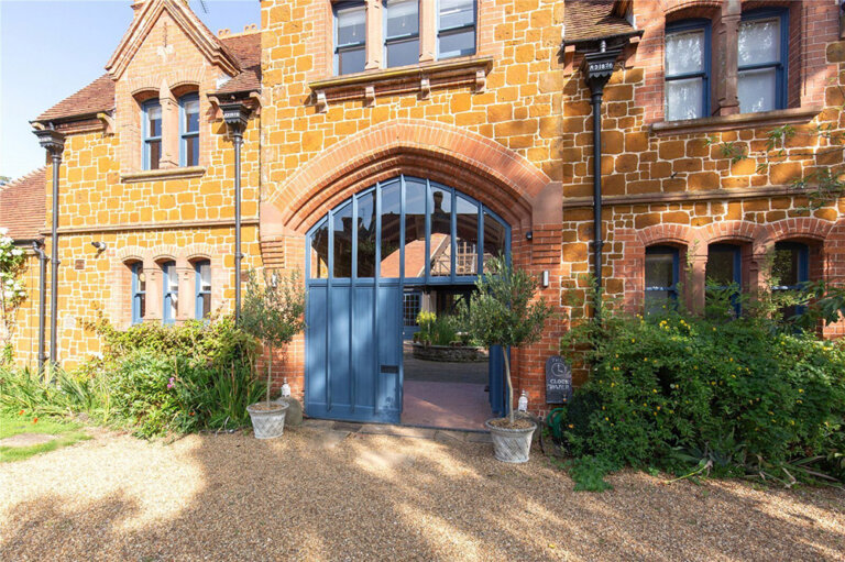 A moated Victorian coach house with clock tower and cottage