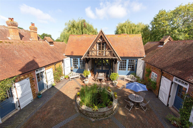 A moated Victorian coach house with clock tower and cottage